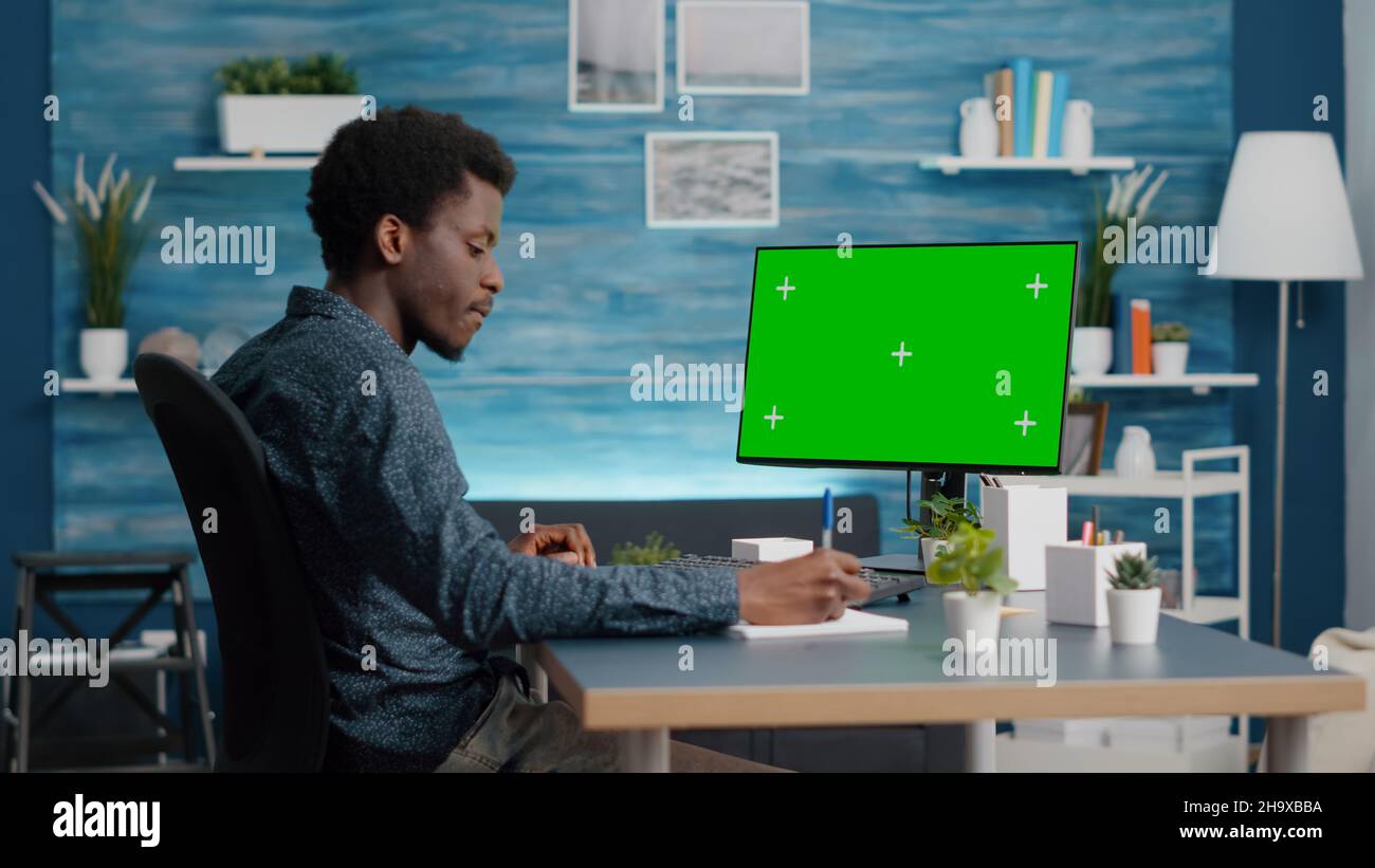 Black man typing and using personal computer with mock up chroma key ...