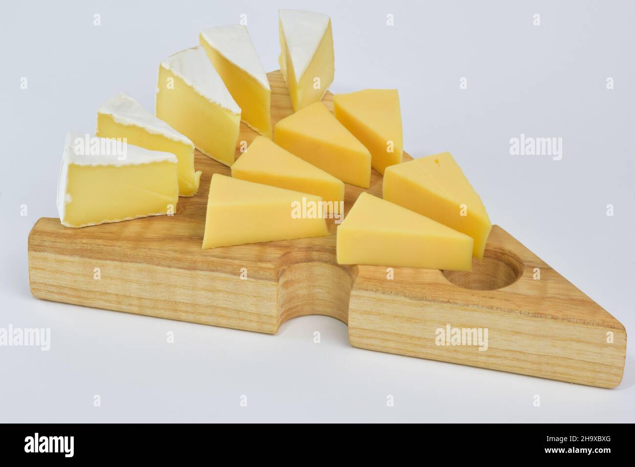 Several pieces of different types of cheese lie on a special wooden ...