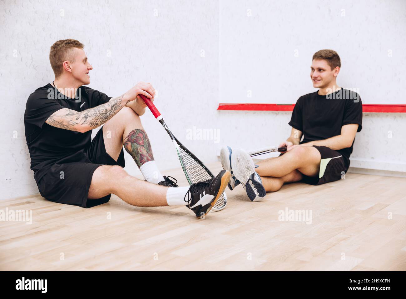 Full-length portrait of two sportive boys, squash players resting after ...