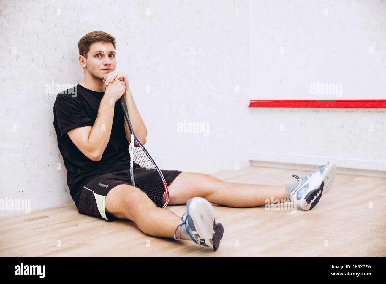 Full-length portrait of young man, squash players resting after ...