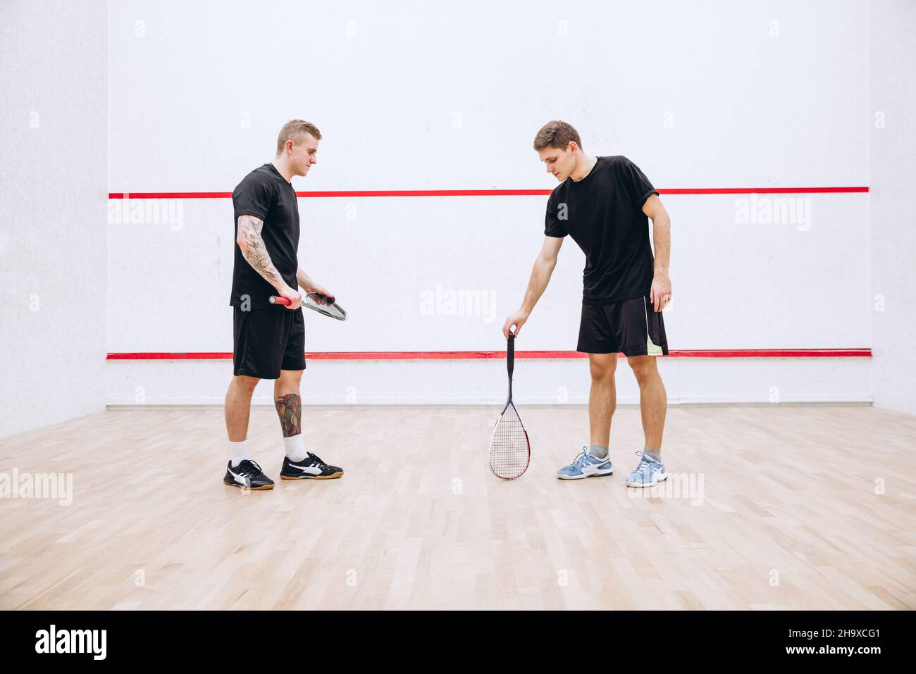 Full-legth portrait of two young sportive men at sport squash studio ...