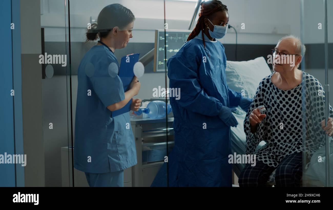 African american surgeon walking elder patient from hospital ward with ...