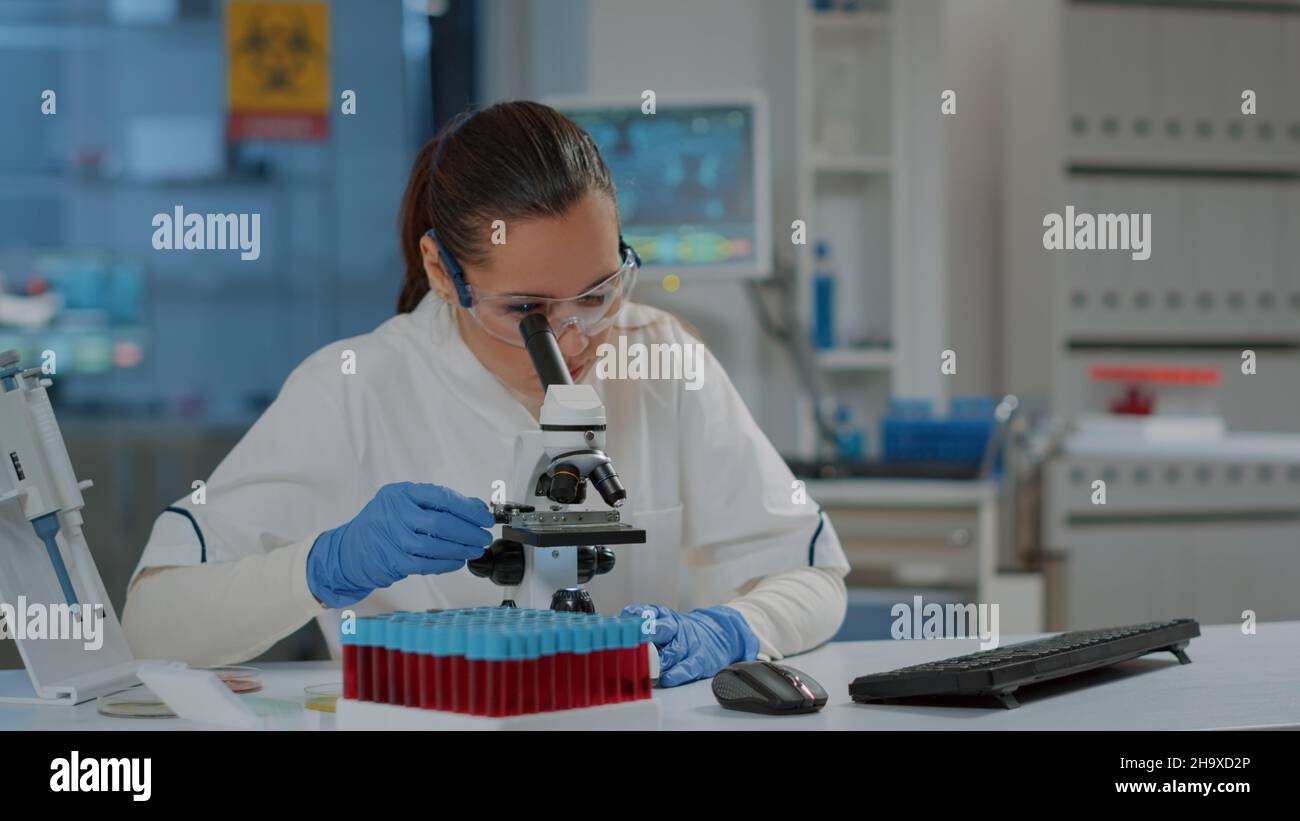 Chemist using microscope to study dna substance in laboratory, looking ...