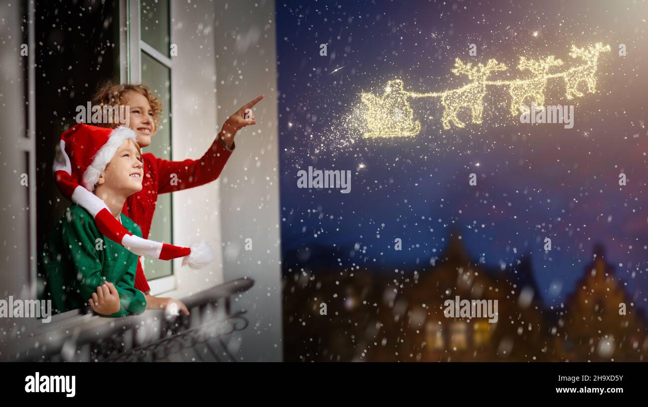 Kids look at Santa fly in the sky on Christmas eve. Children watch ...