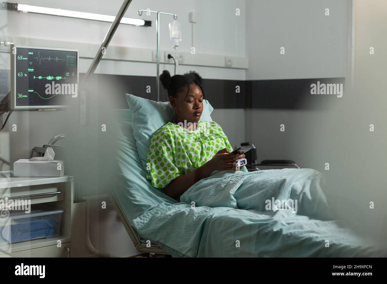 African american sick patient lying in bed holding modern phone ...