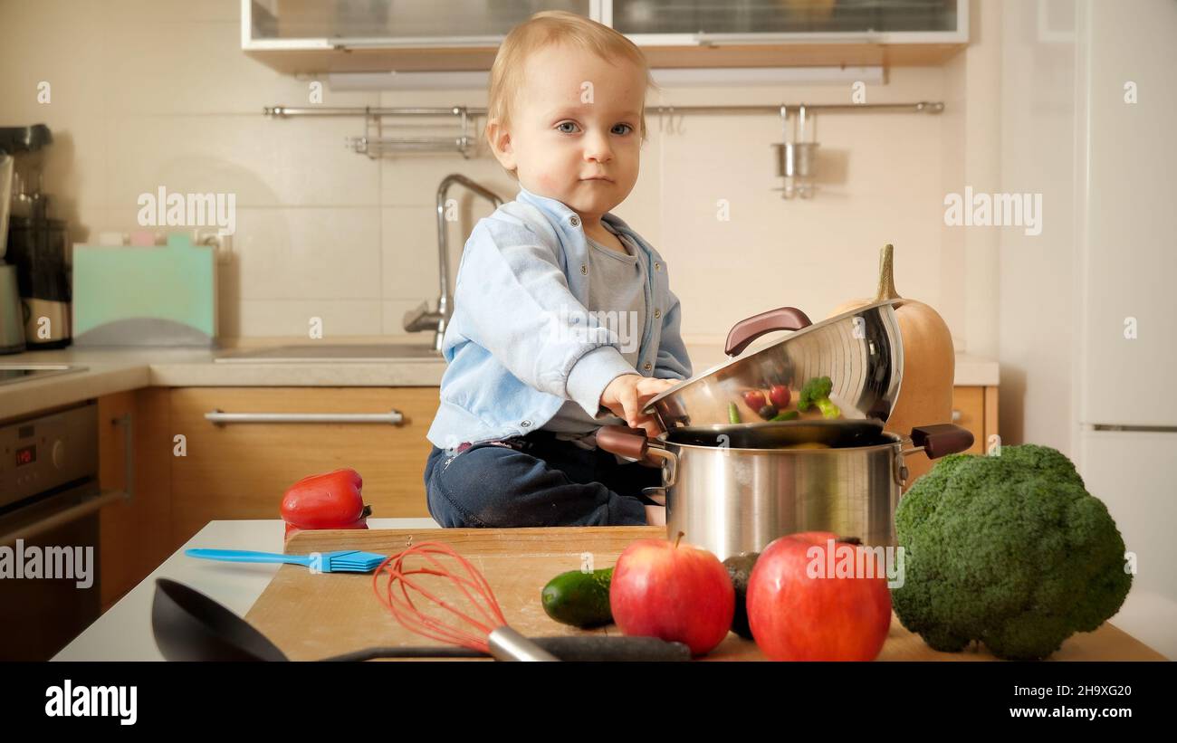 Cute little baby boy playing with metal pans, glass lids and bowl on ...