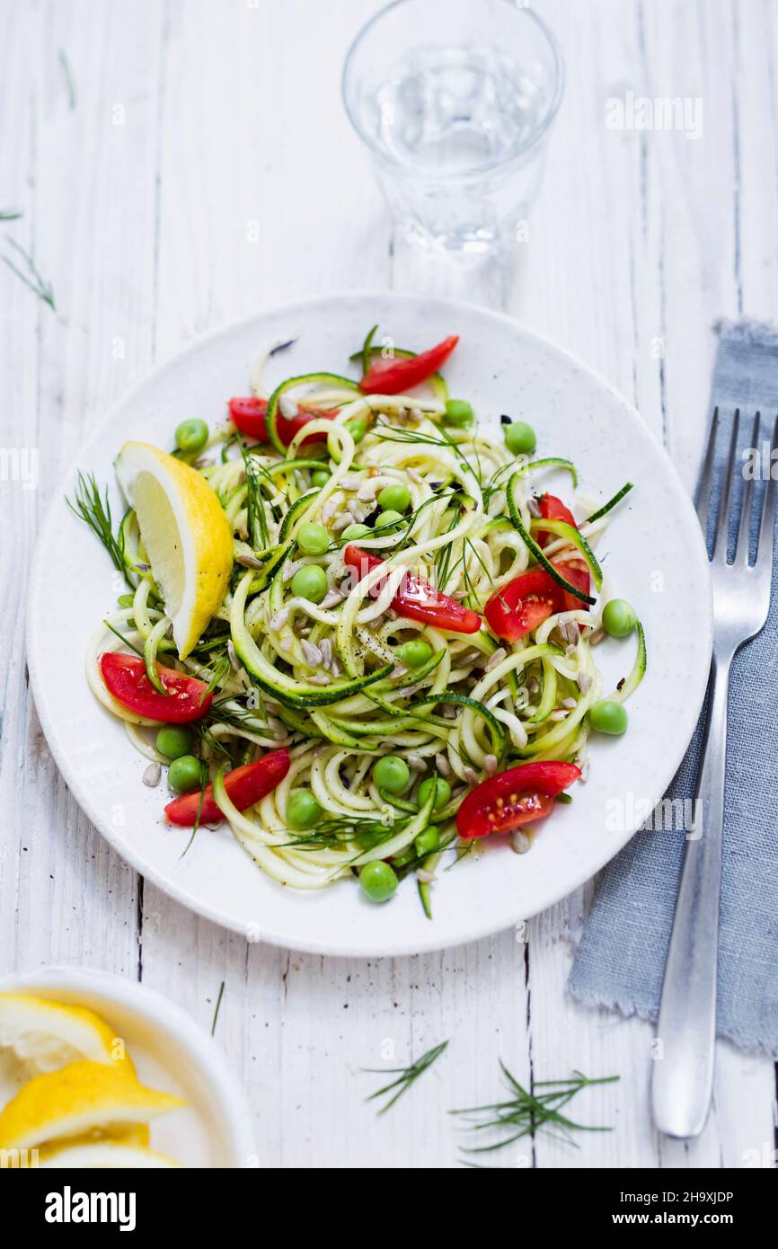 Courgette spaghetti with tomatoes and peas Stock Photo - Alamy