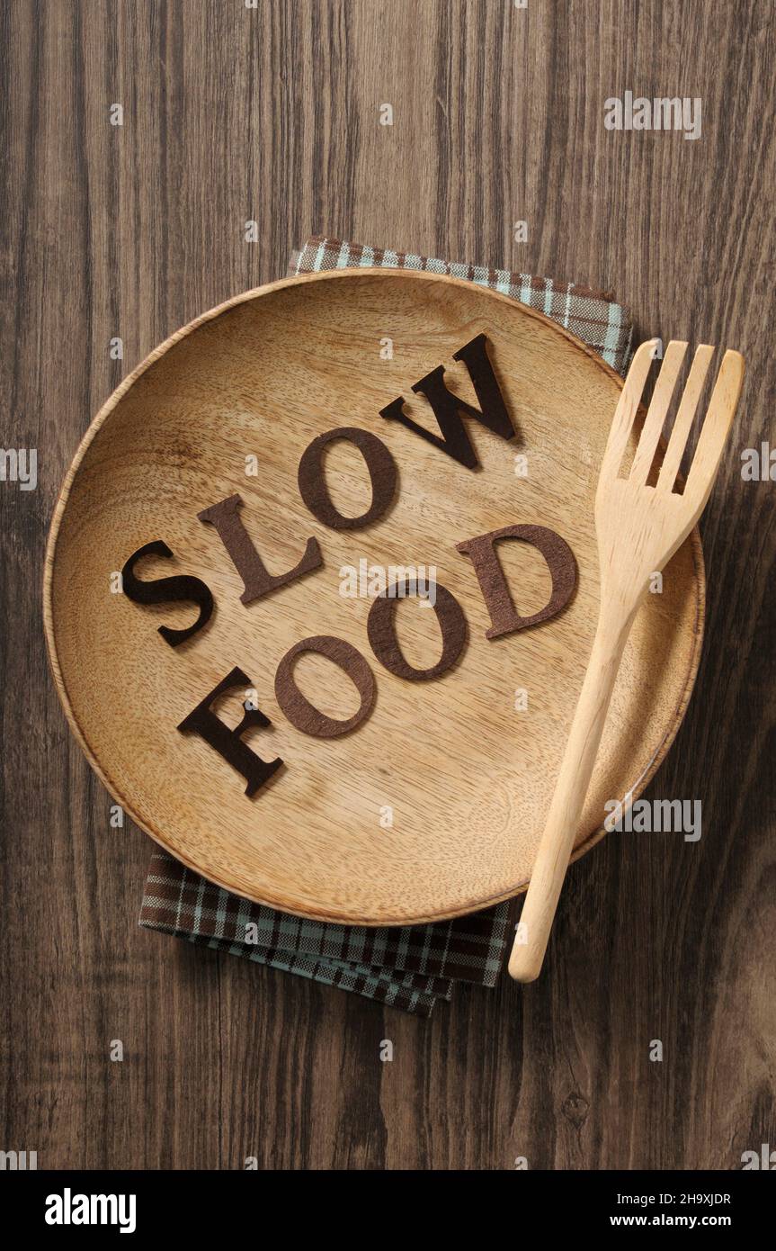 'Slow Food' written on a wooden plate with a fork Stock Photo - Alamy