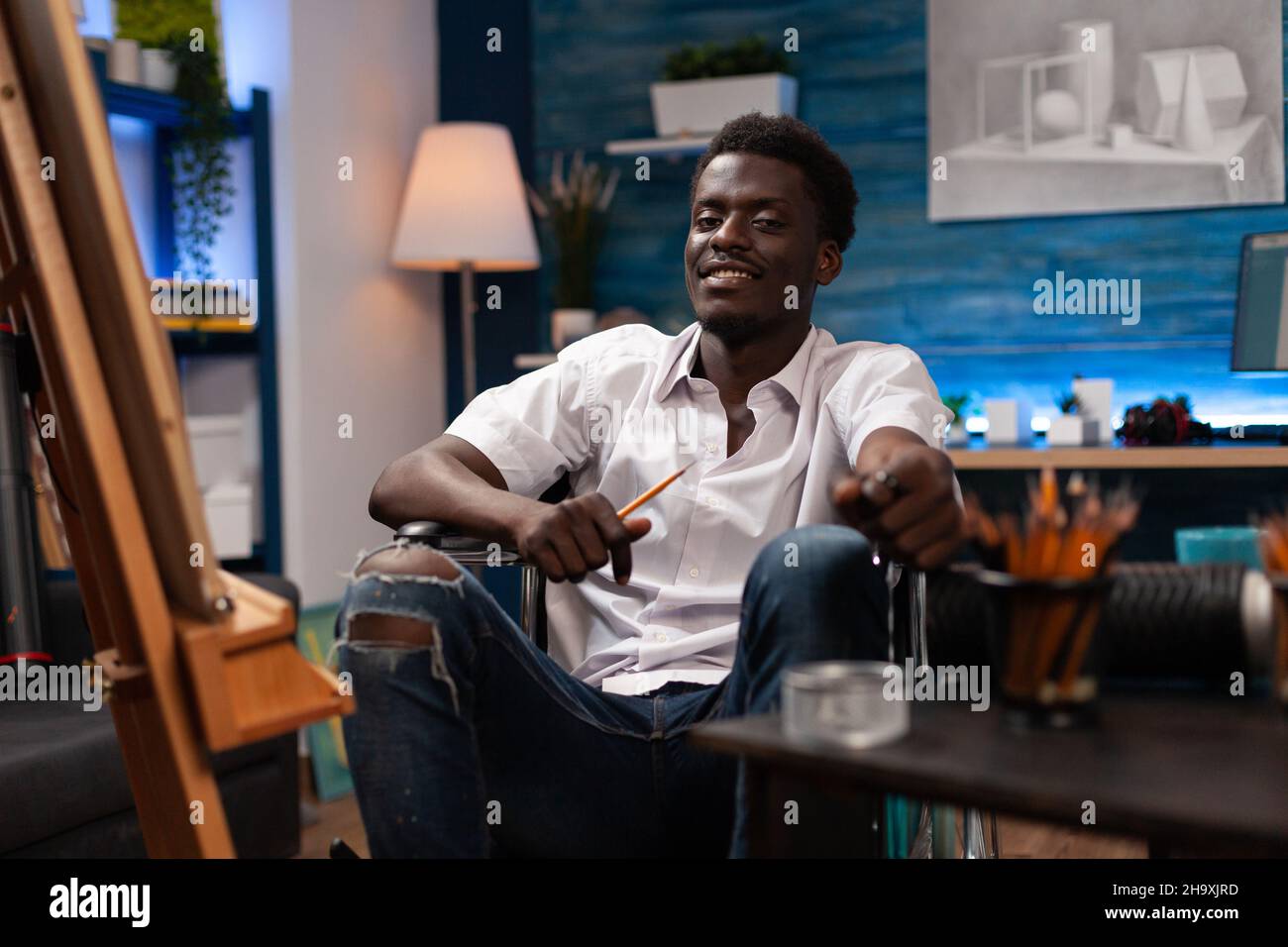 Portrait of young illustrator with disability smiling at camera while ...