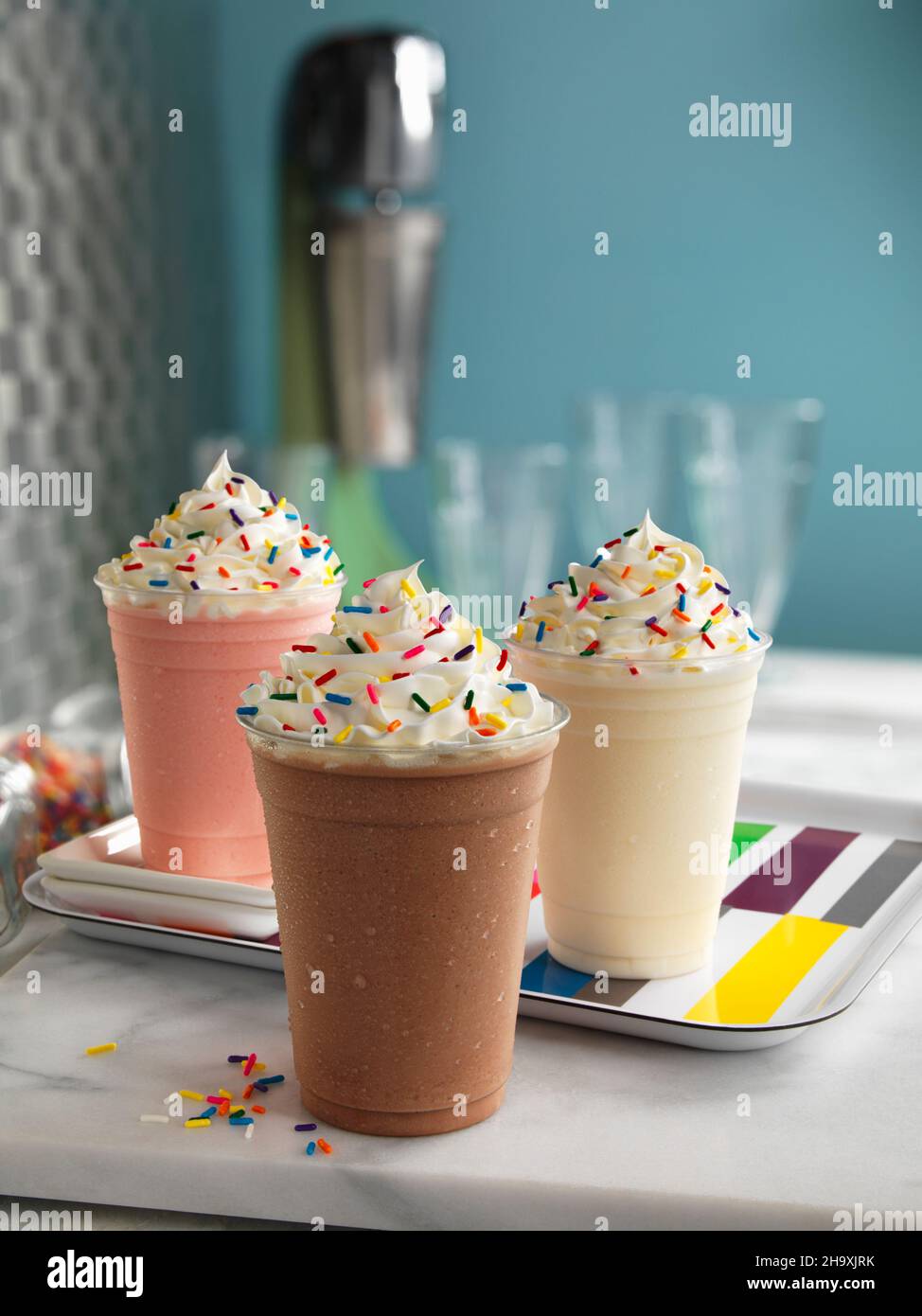 Three different milk shakes with cream and colourful sugar sprinkles ...