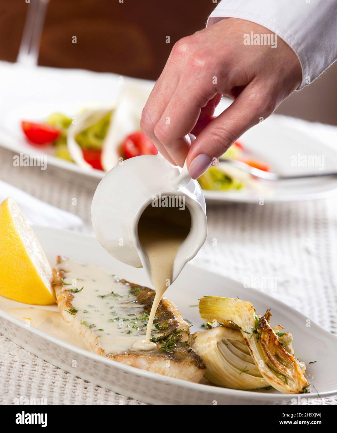 Sauce being poured over a fish fillet Stock Photo - Alamy