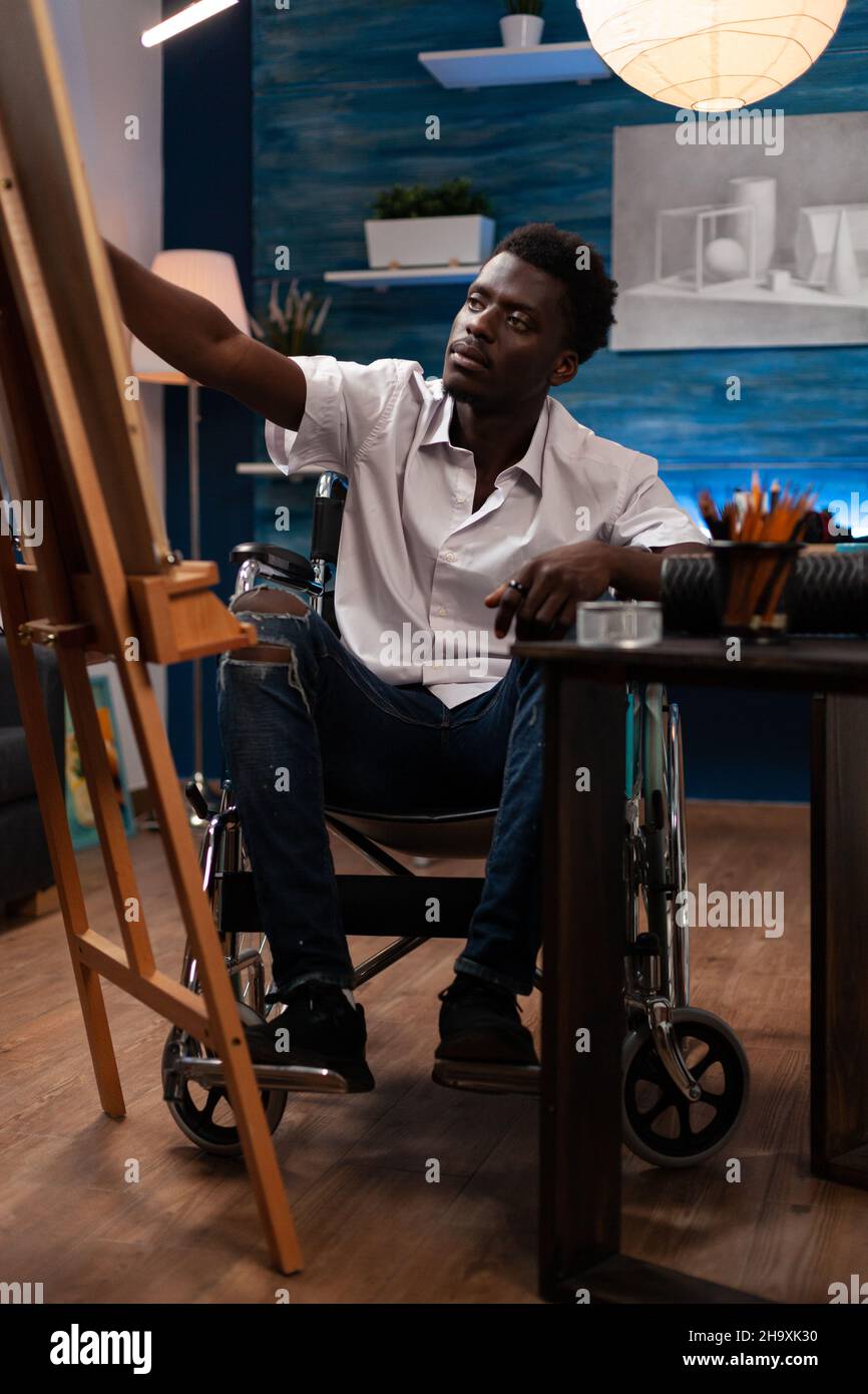 Young artist in wheelchair drawing sketch on canvas working at creative ...