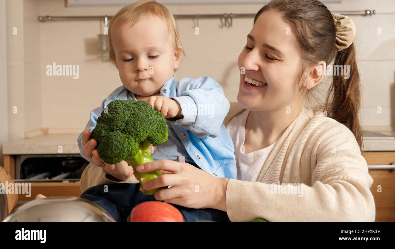 Cute baby boy exploring kitchen utensils, fruits and vegetables on ...