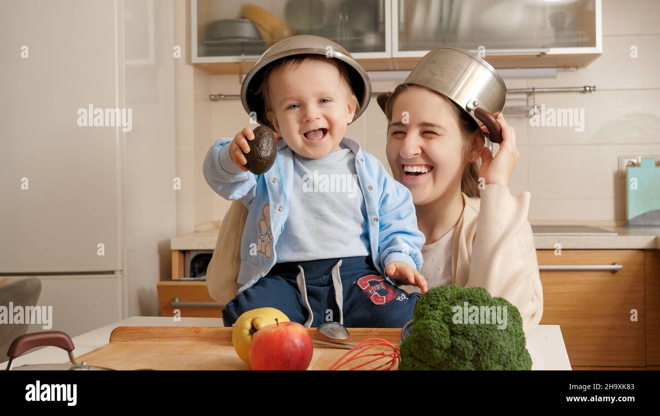 Happy laughing mother with baby son playing on kitchen with cooking ...