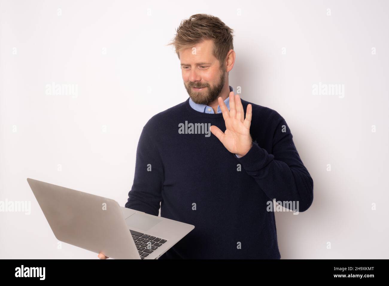 Young smiling handsome man using laptop computer standing isolated over ...