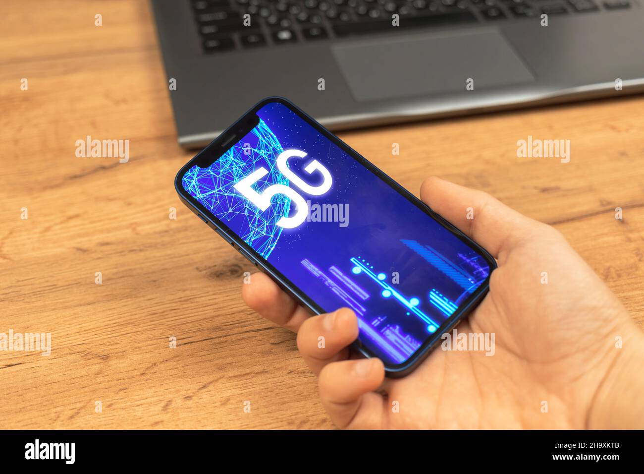 Hand uses mobile phone with 5G network. Business desktop background ...