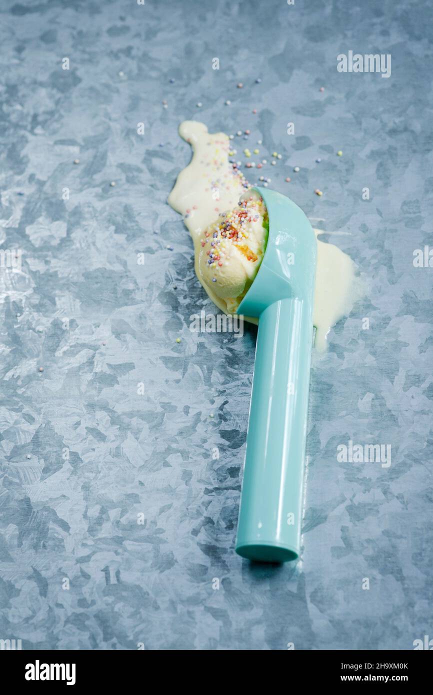 An ice cream scoop with a scoop of melting vanilla ice cream and sugar ...
