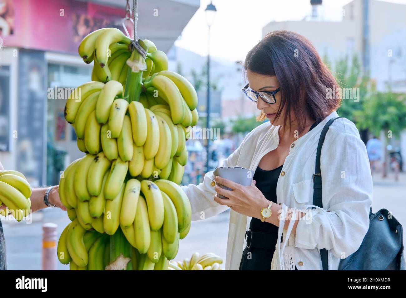 Woman buying bananas at a street retail market Stock Photo - Alamy