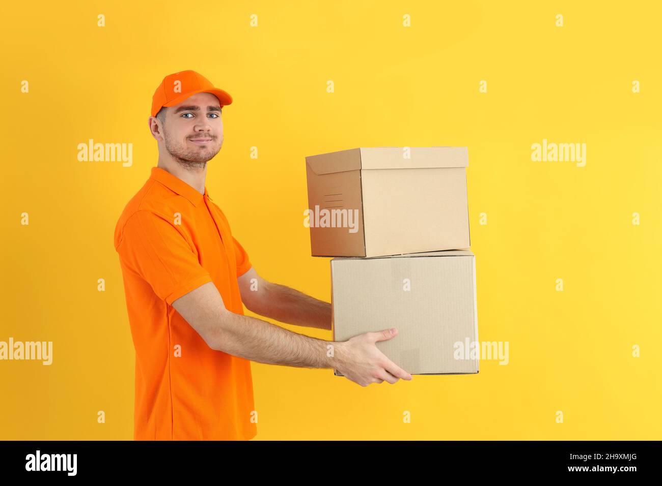 Delivery guy hold boxes on yellow background Stock Photo - Alamy