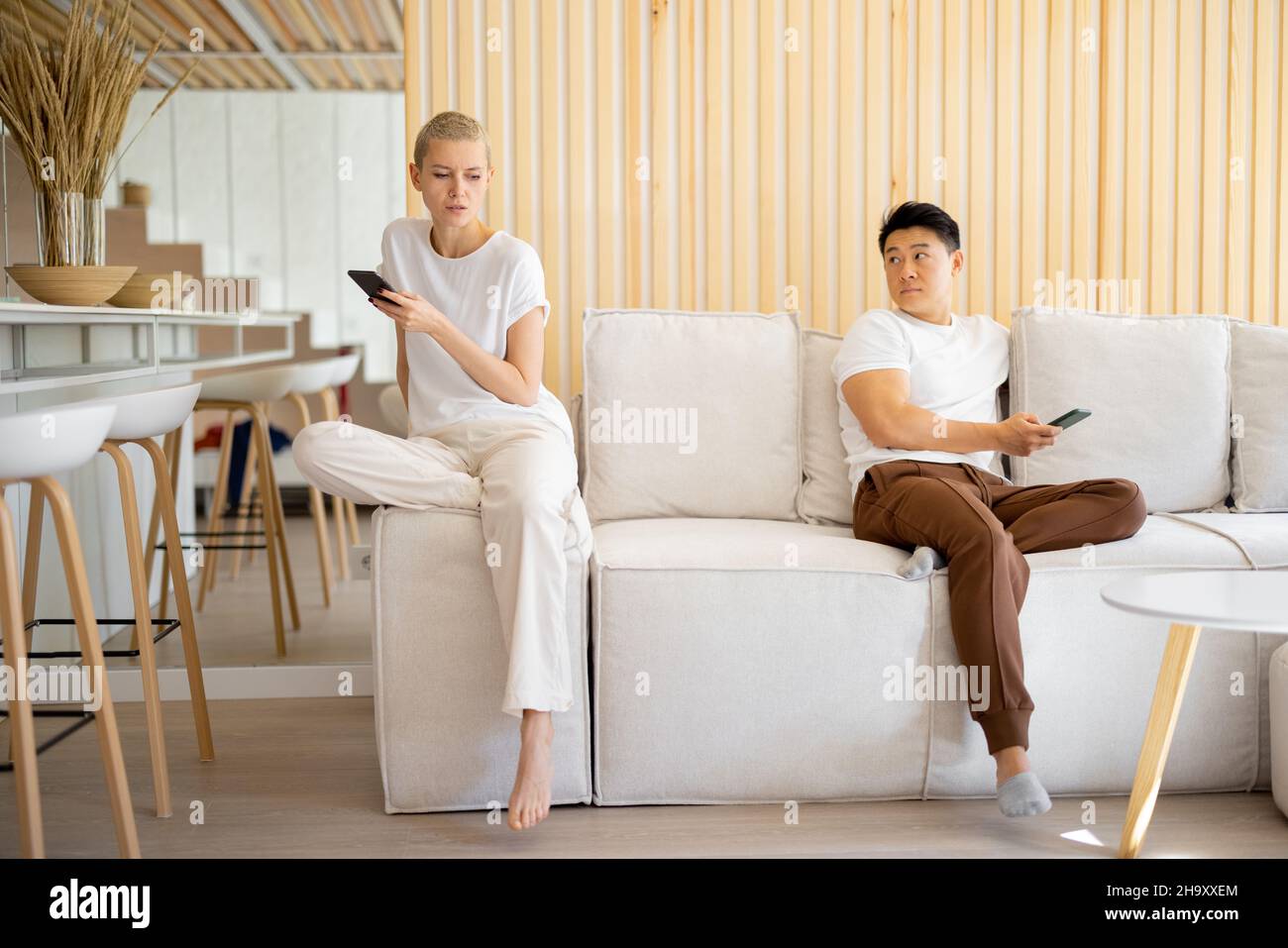 Couple using smartphones on sofa at home Stock Photo - Alamy