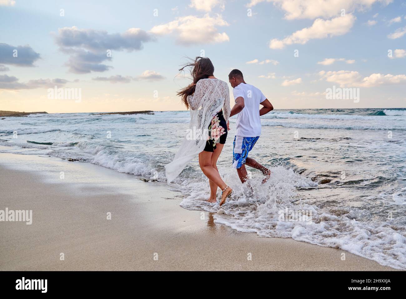 Happy couple running together on beach on summer day, back view Stock ...
