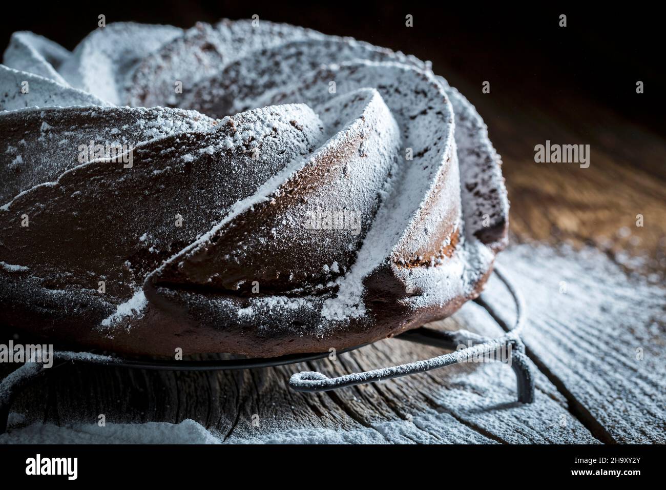 Dark chocolate cake dusted with icing sugar on a wooden table Stock ...