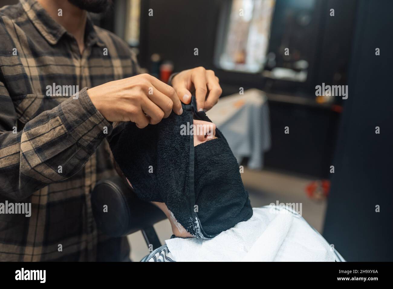 Barber preparing man face for shaving with hot towel in barber shop ...