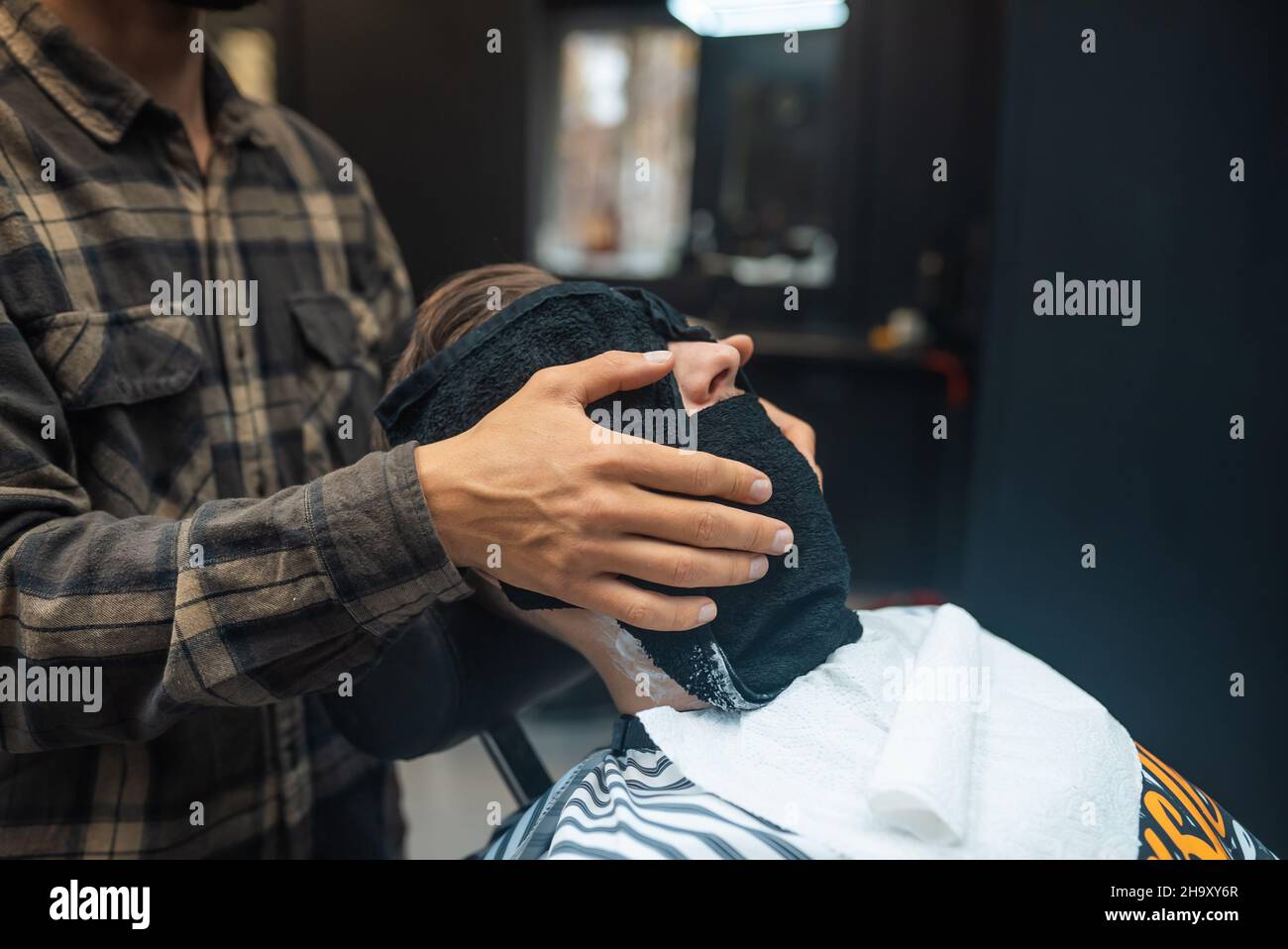 Barber preparing man face for shaving with hot towel in barber shop ...
