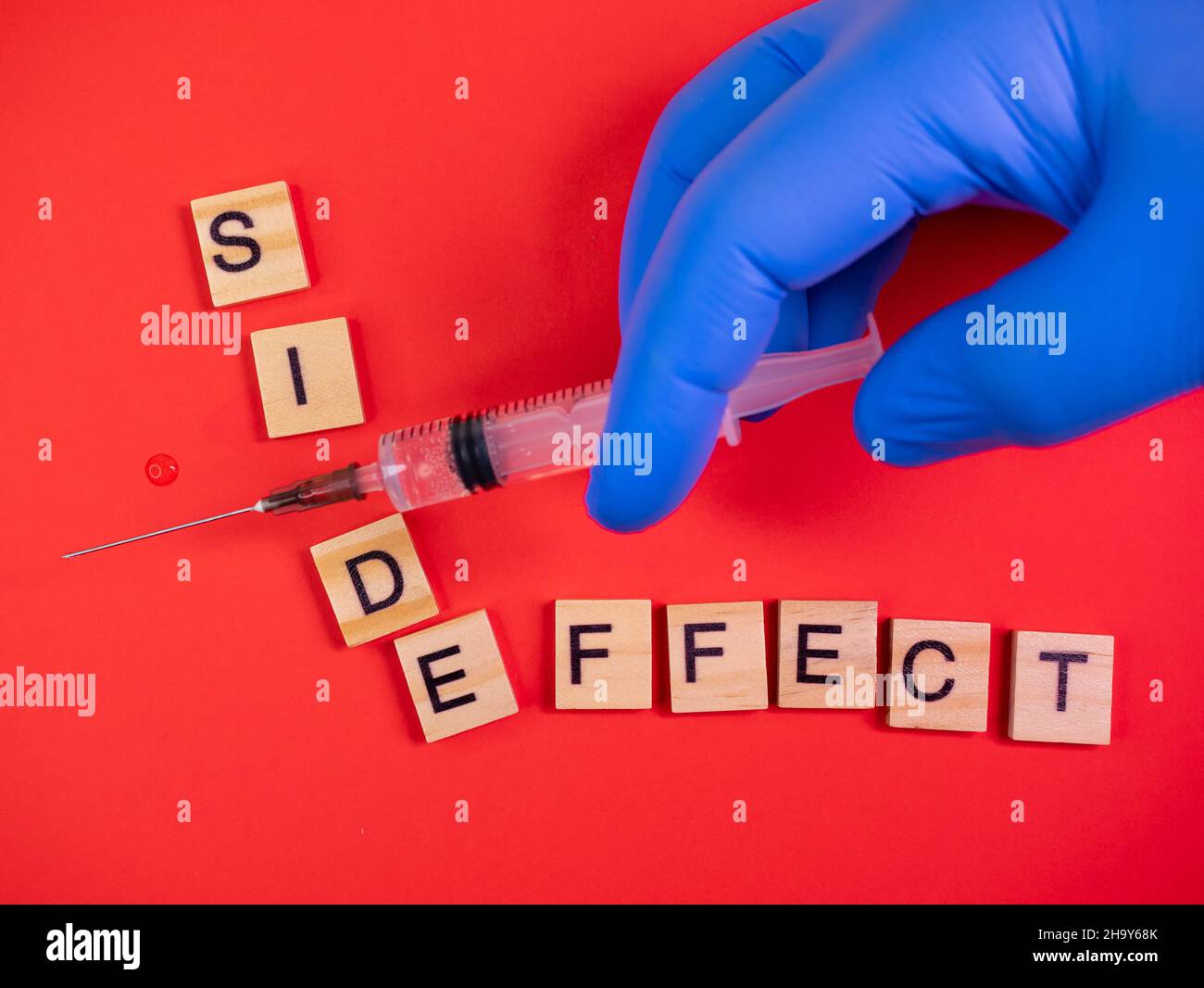 Syringe filled with solution. Words side effect on colored red paper ...