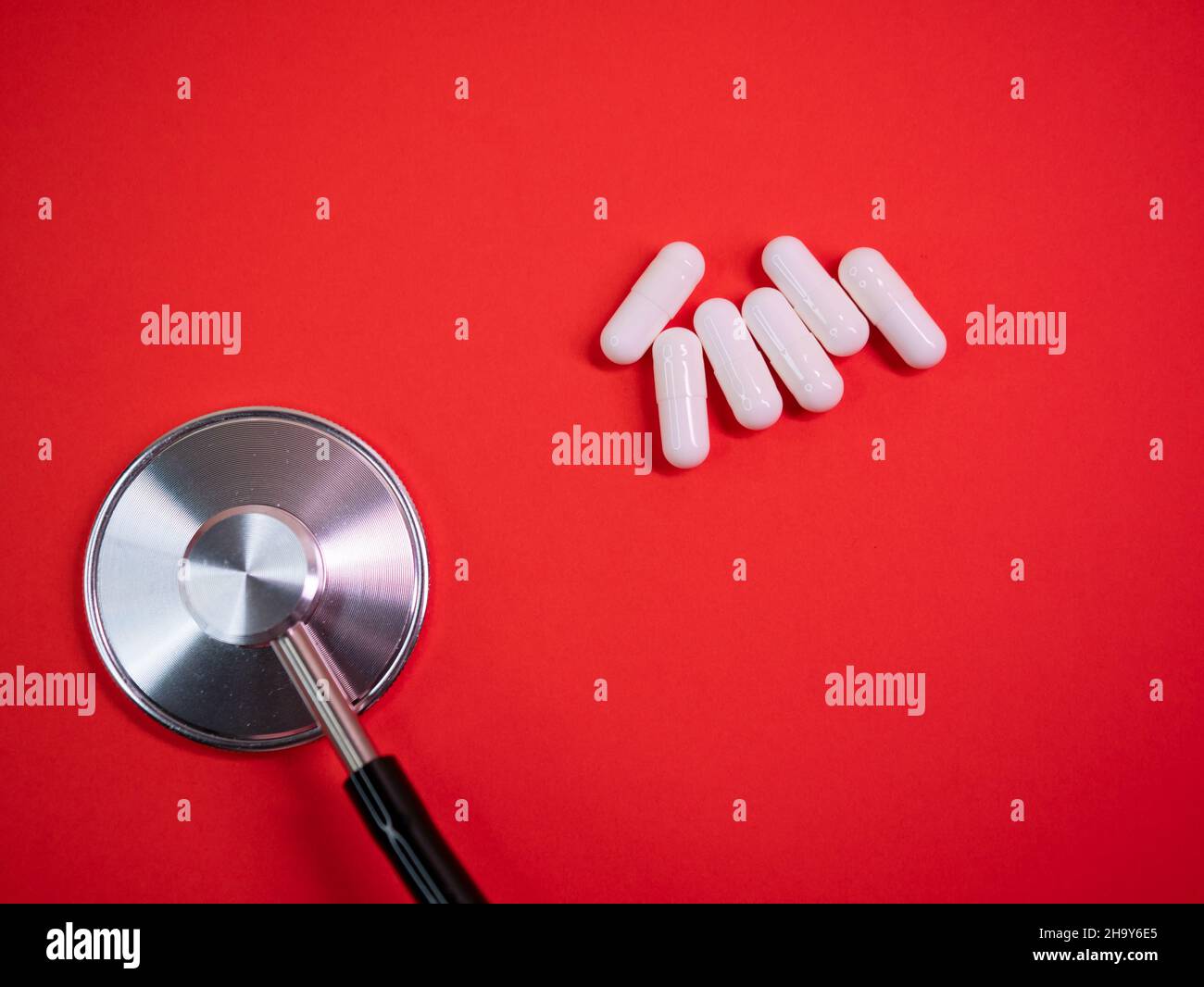 White drug capsules on colored red paper texture background. Macro ...