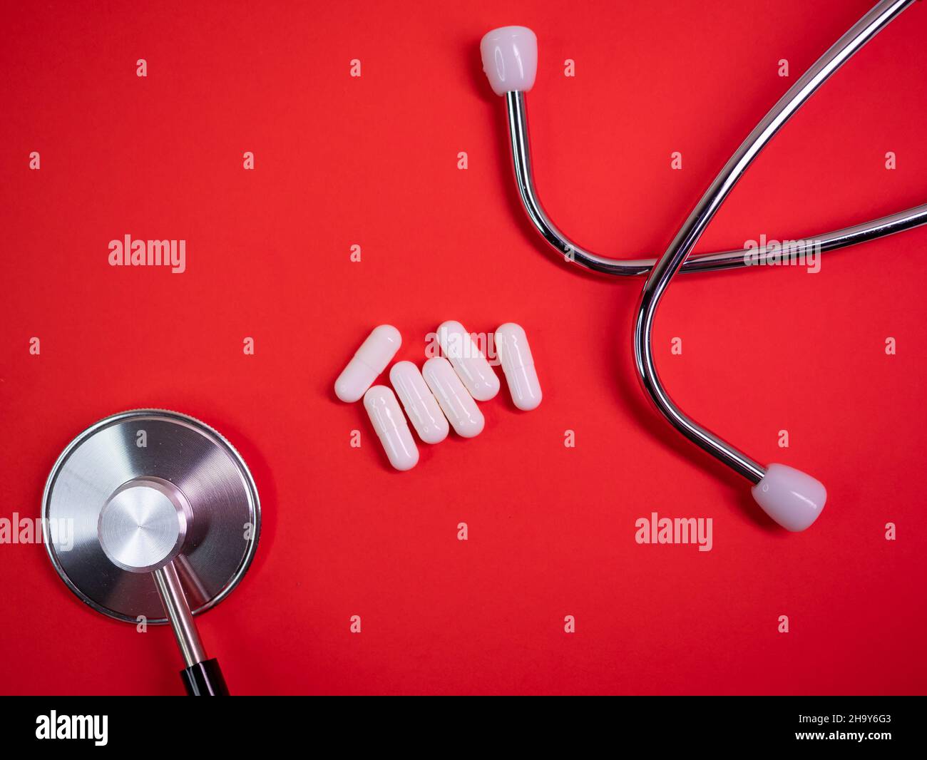 White drug capsules on colored red paper texture background. Macro ...