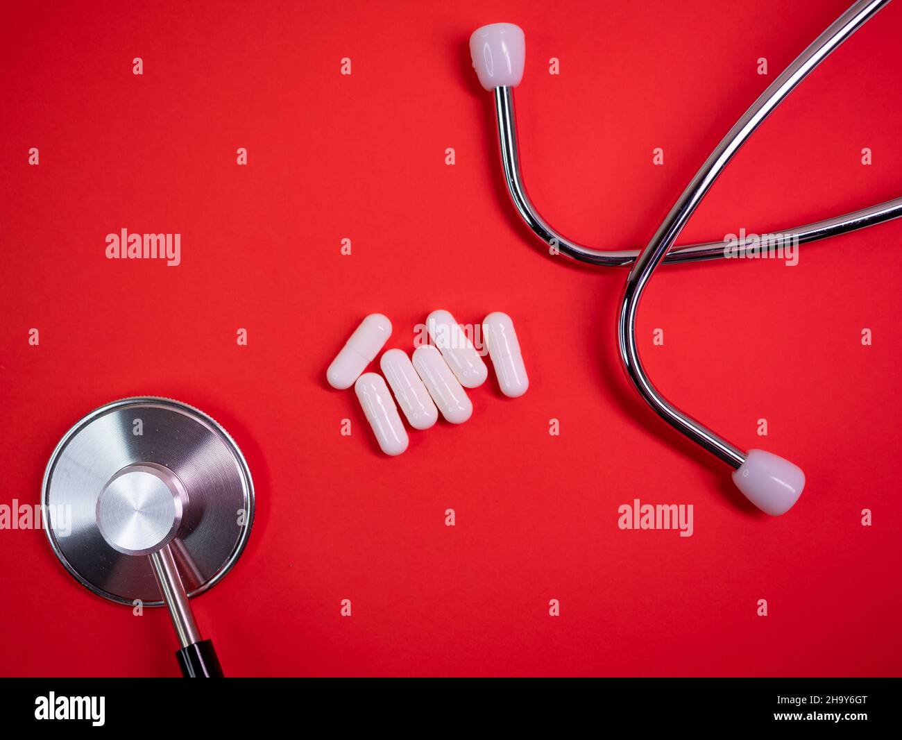 White drug capsules on colored red paper texture background. Macro ...