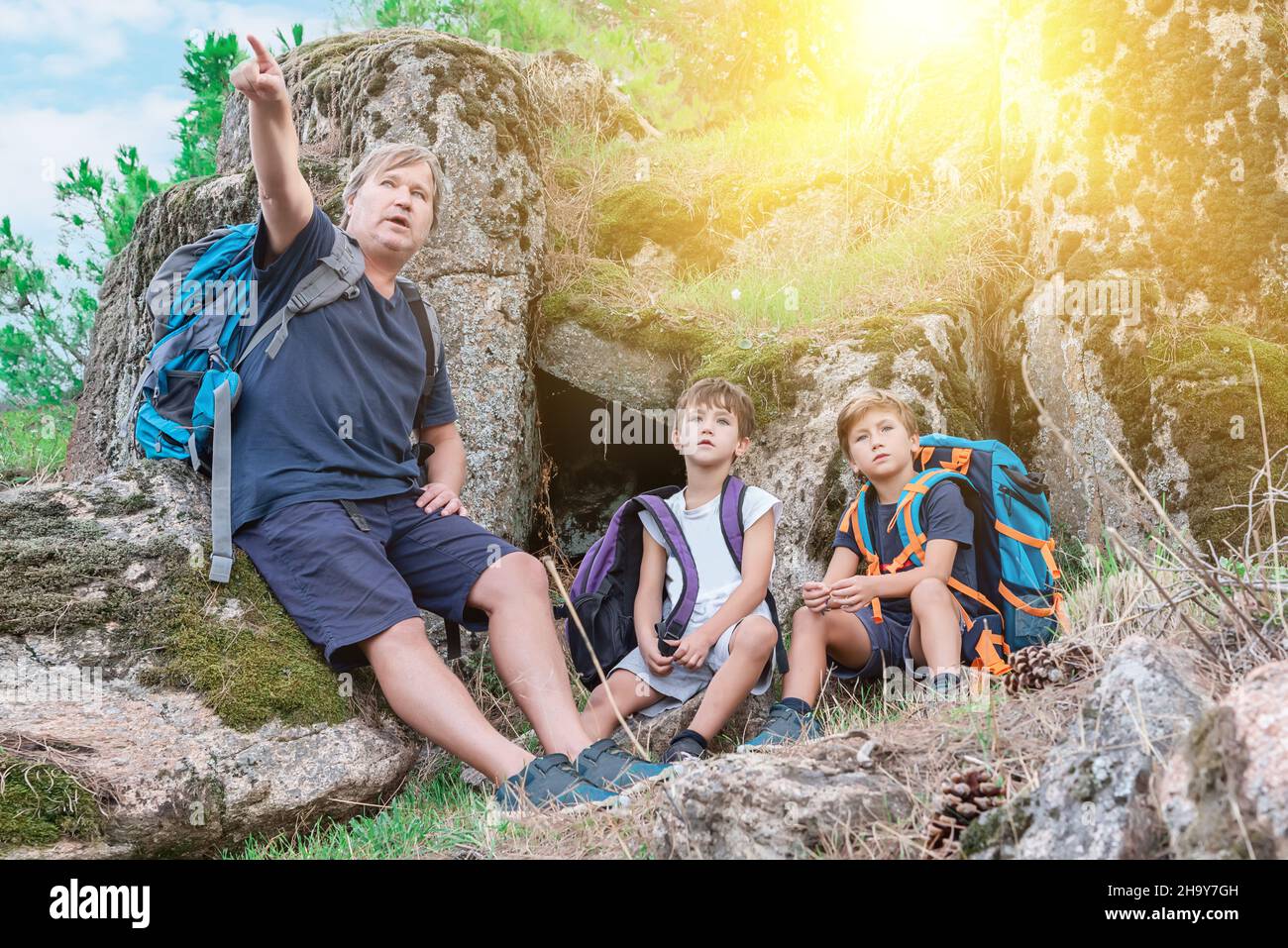 Boy scout monitor sitting on a rock and resting next to two boy hikers ...