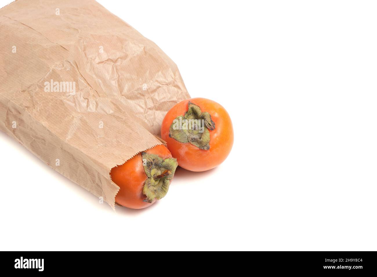 Persimmon fruit in a grocery paper bag on a white background Stock ...