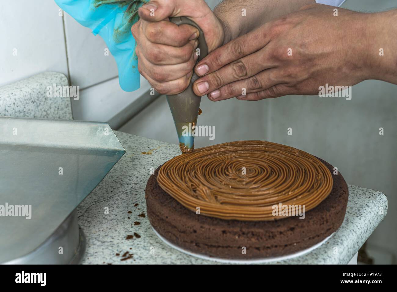 Close up view of a pastry chef making a chocolate truffle cake using a ...