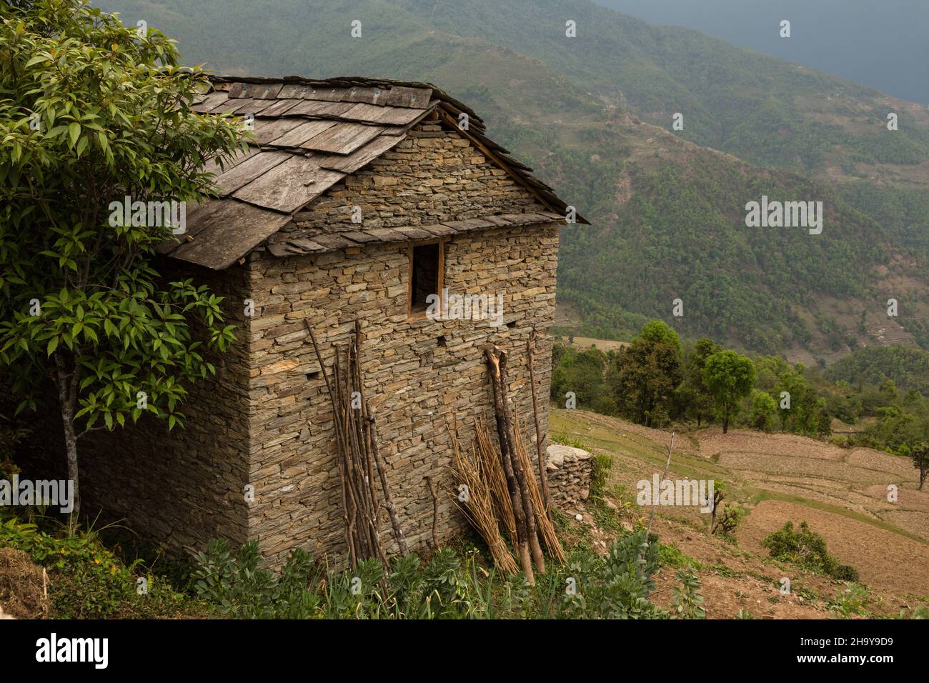 A traditional Nepalese farm building of stone with a slate tile roof in ...