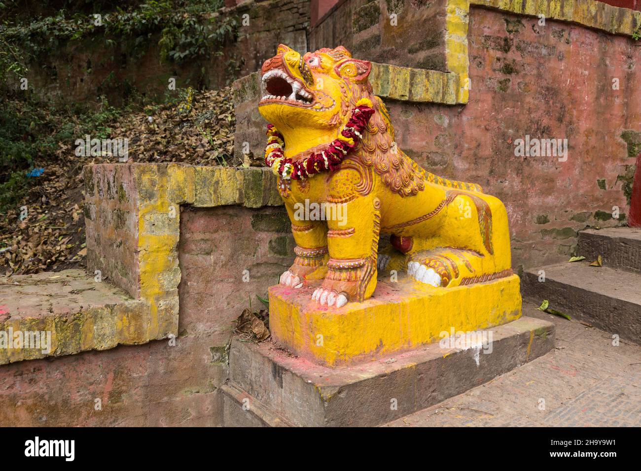A temple guardian lion with a flower garland at the entrance to the ...