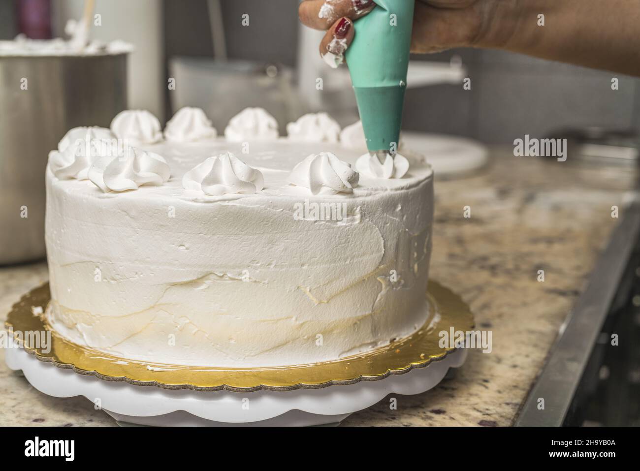 Closeup sho of a female pastry chef garnishing a white cake with cream ...