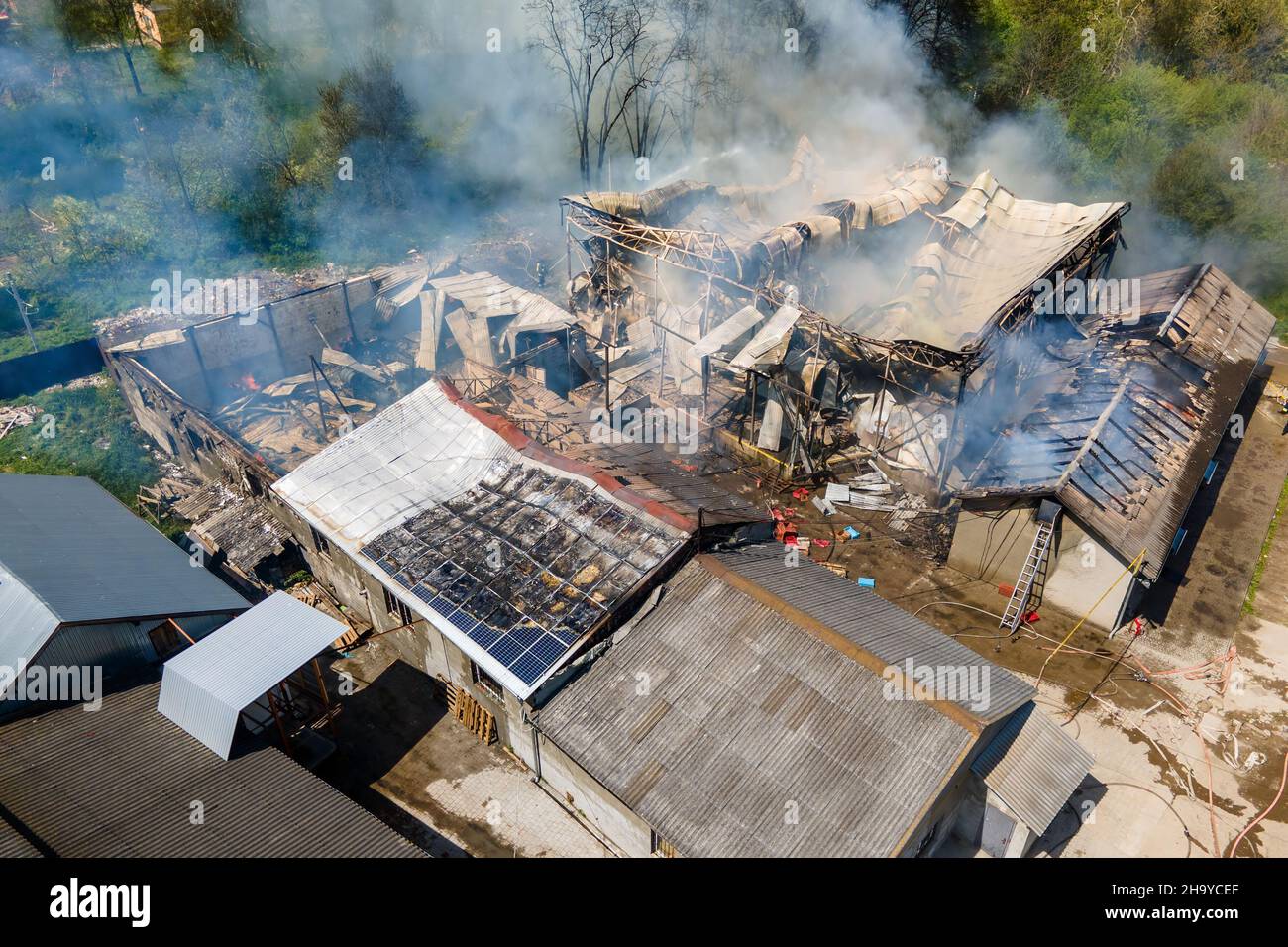 Aerial view of ruined building on fire with collapsed roof and rising ...