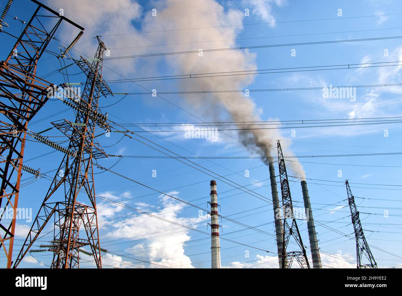 High voltage electric pylons against coal power plant high pipes with ...