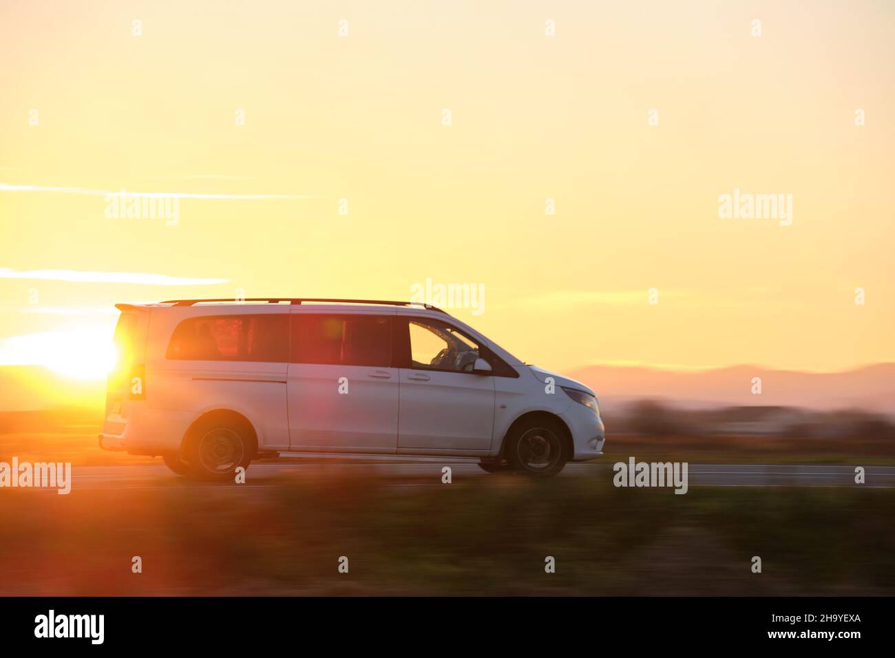 Passenger van driving fast on intercity road at sunset. Highway traffic ...