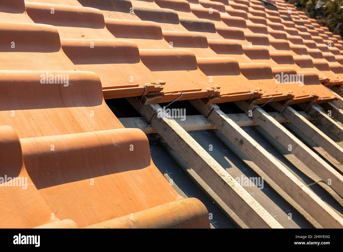 Overlapping rows of yellow ceramic roofing tiles mounted on wooden ...