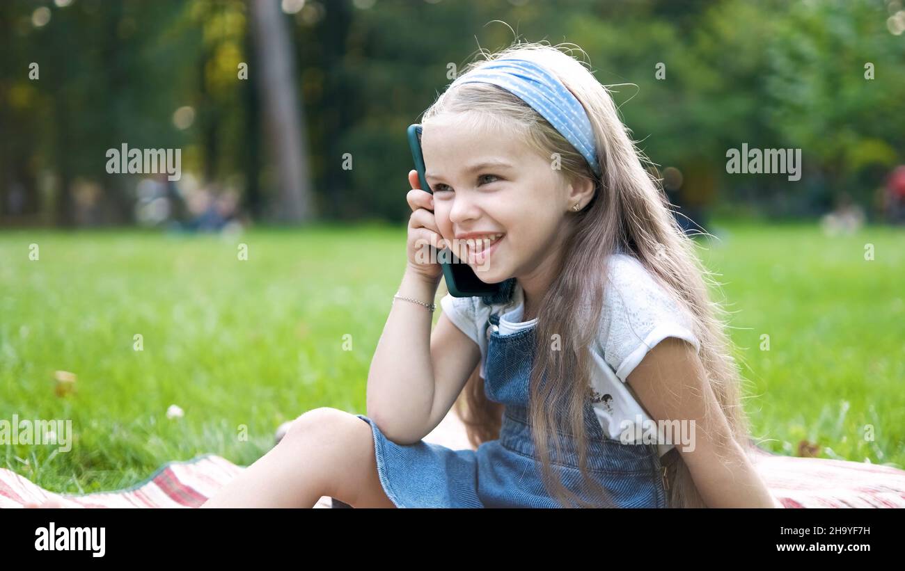 Pretty little child girl having conversation on her mobile phone in ...