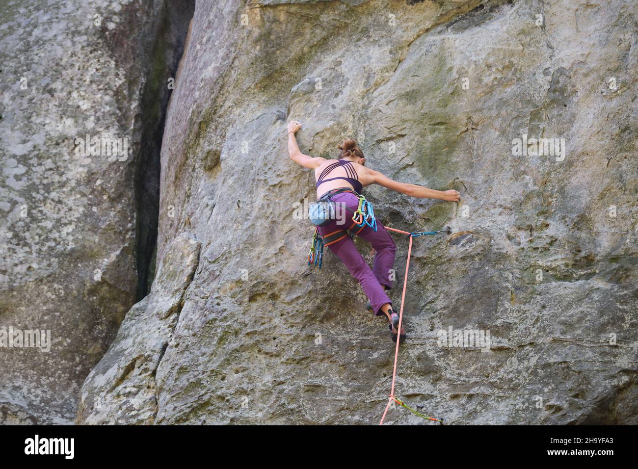 Strong female climber climbing steep wall of rocky mountain ...