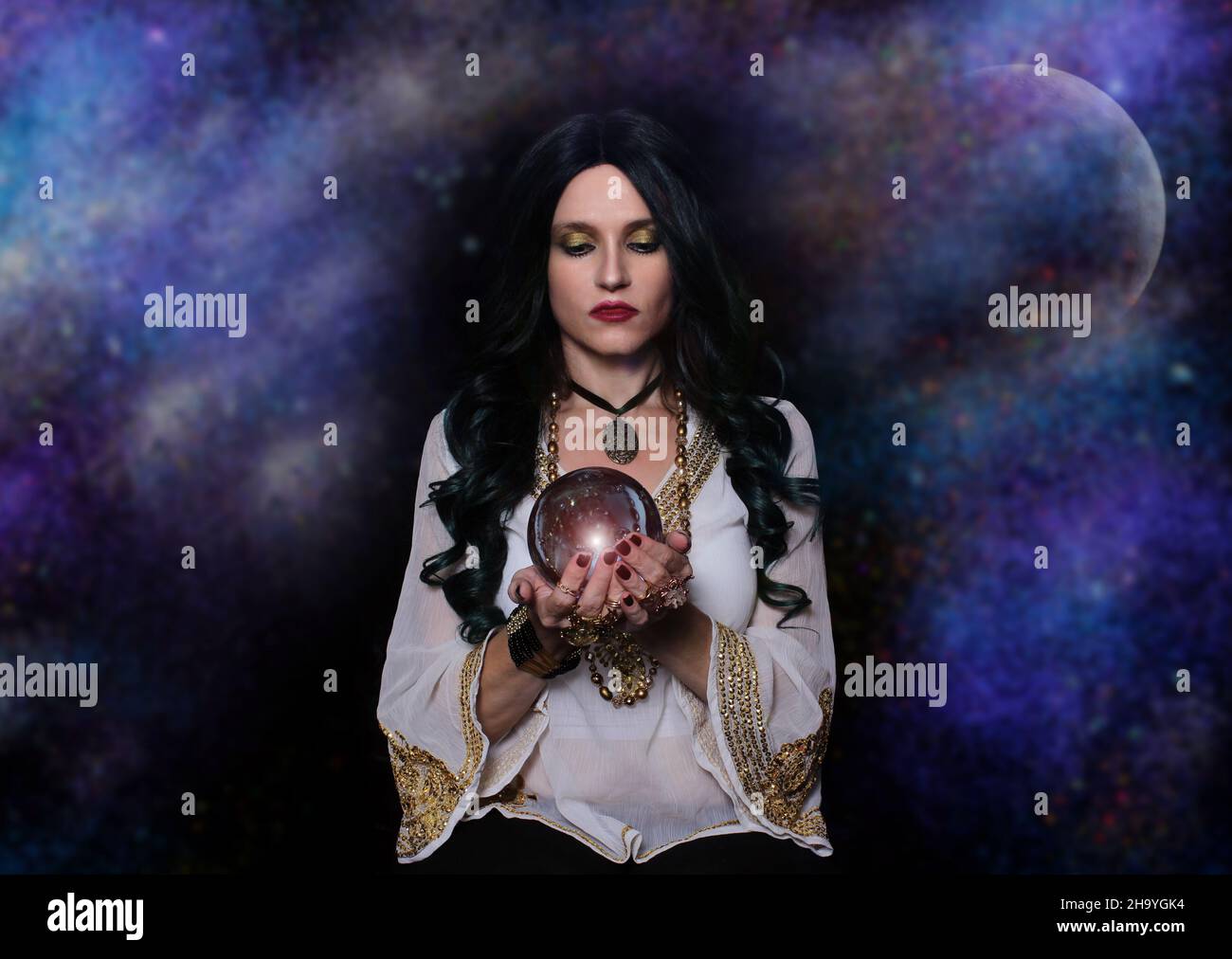 Female Psychic with Crystal Ball and galaxy background Stock Photo - Alamy