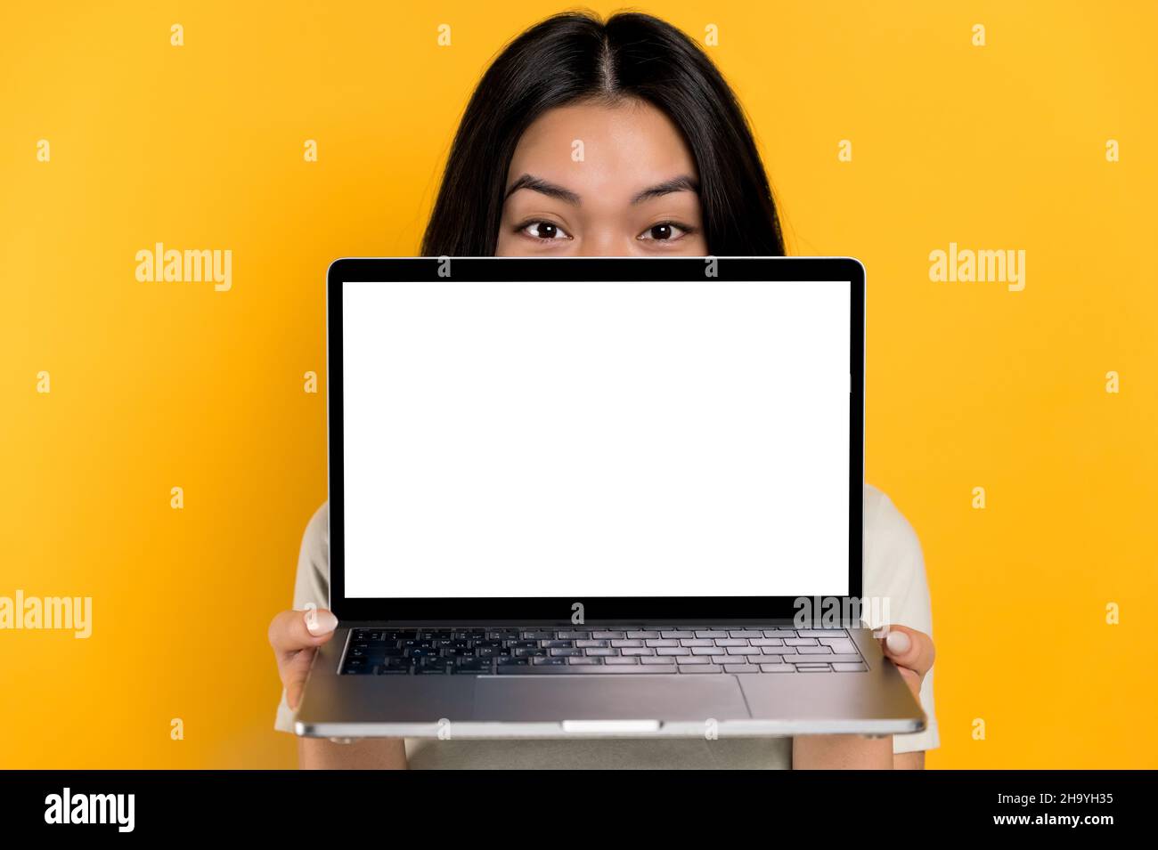 Amazed excited brunette asian young woman peeking out from behind ...