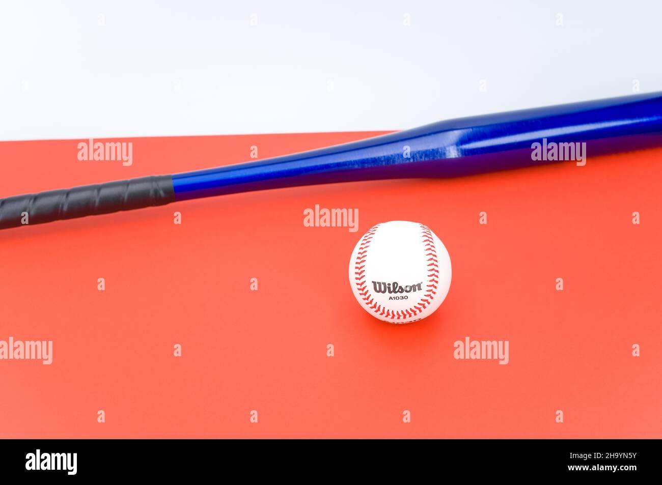 INVERIGO, ITALY - Dec 08, 2021: isolated baseball ball and bat on a red ...