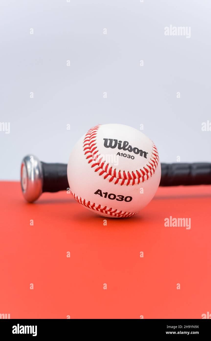 INVERIGO, ITALY - Dec 08, 2021: isolated baseball ball and bat on a red ...