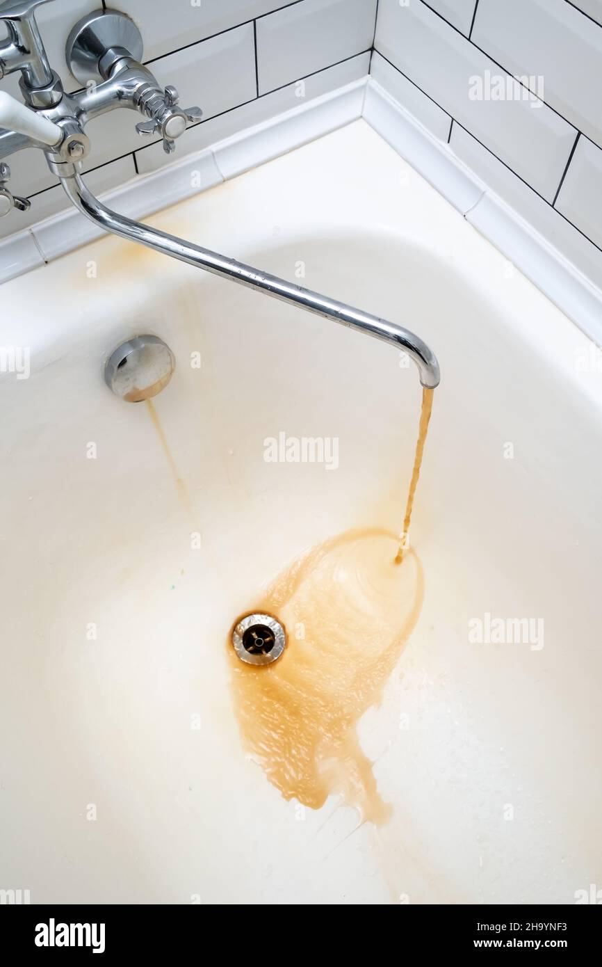 Rusty water flows out of the faucet into a white tub. Problem is old ...