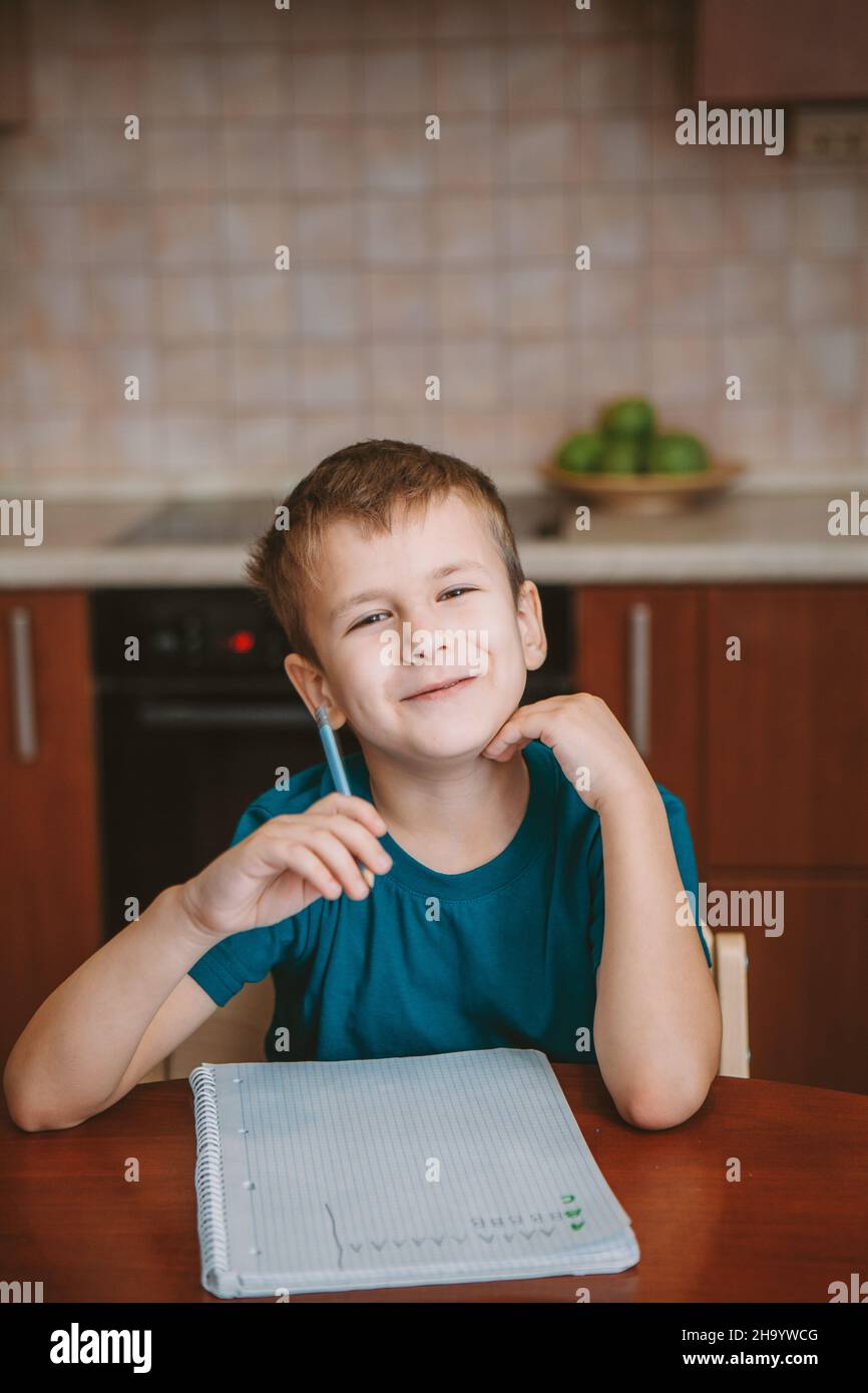 Cute child writing letters in notebook sitting by table Stock Photo - Alamy